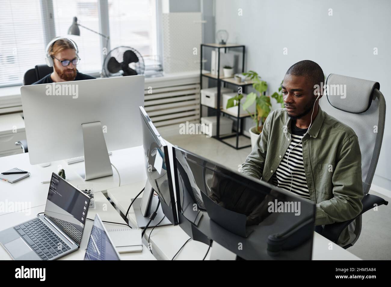 Young serious diversity programmer in casual clothes looking through ...