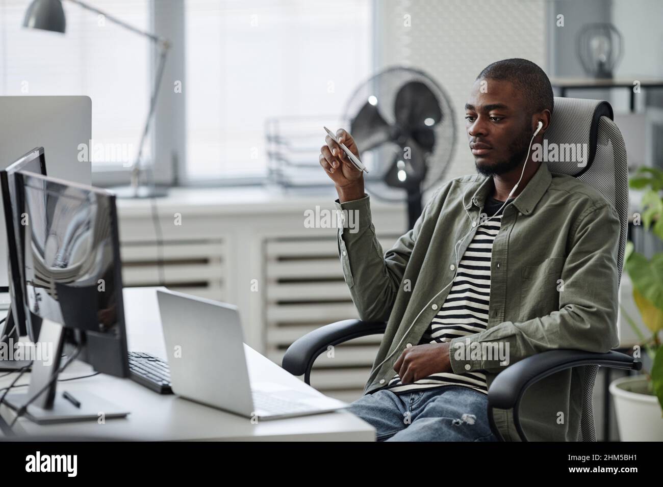 Young serious African American diversity programmer sitting in armchair ...