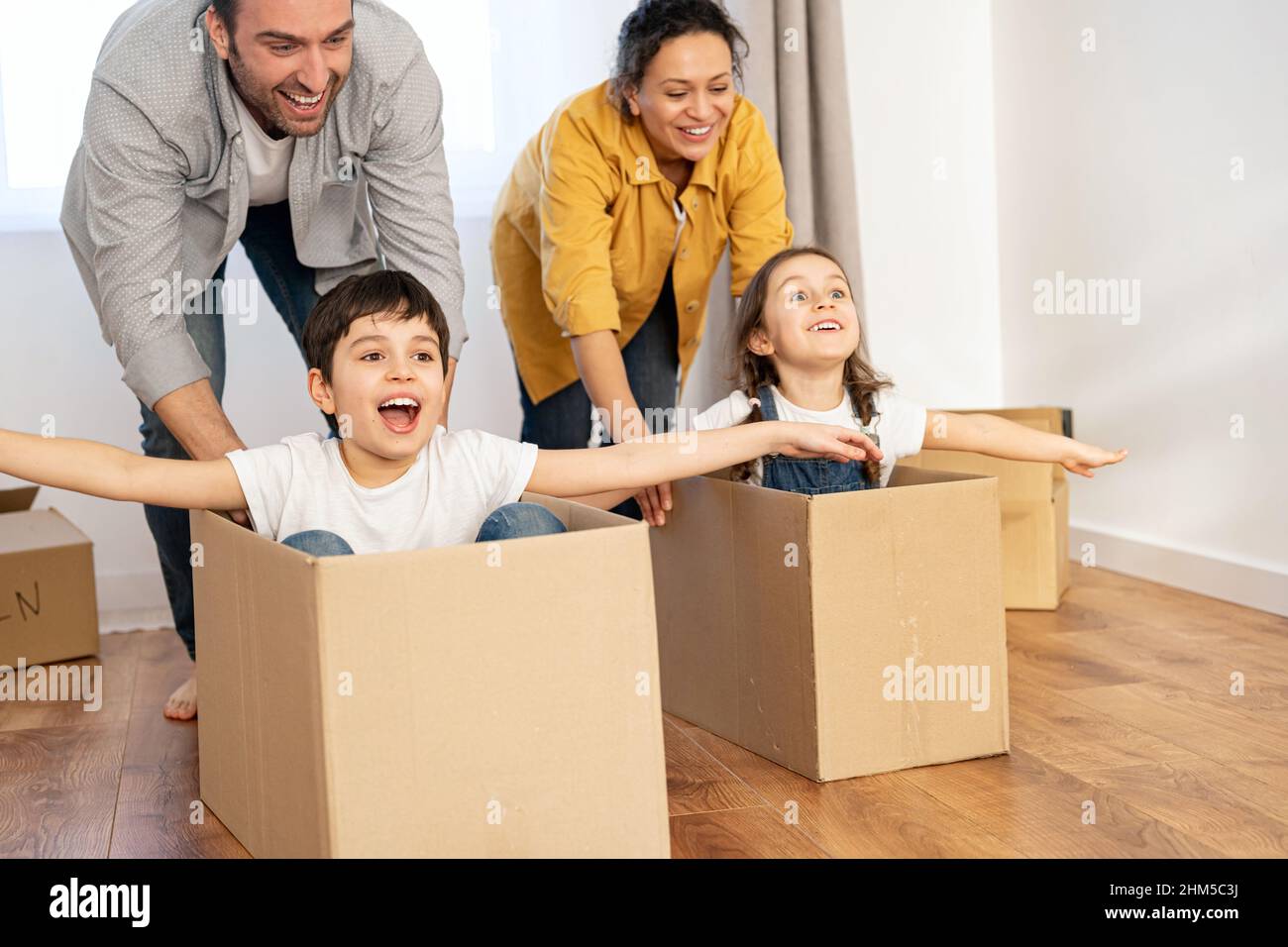 Multiracial family of four have fun in new house, parents riding kids ...