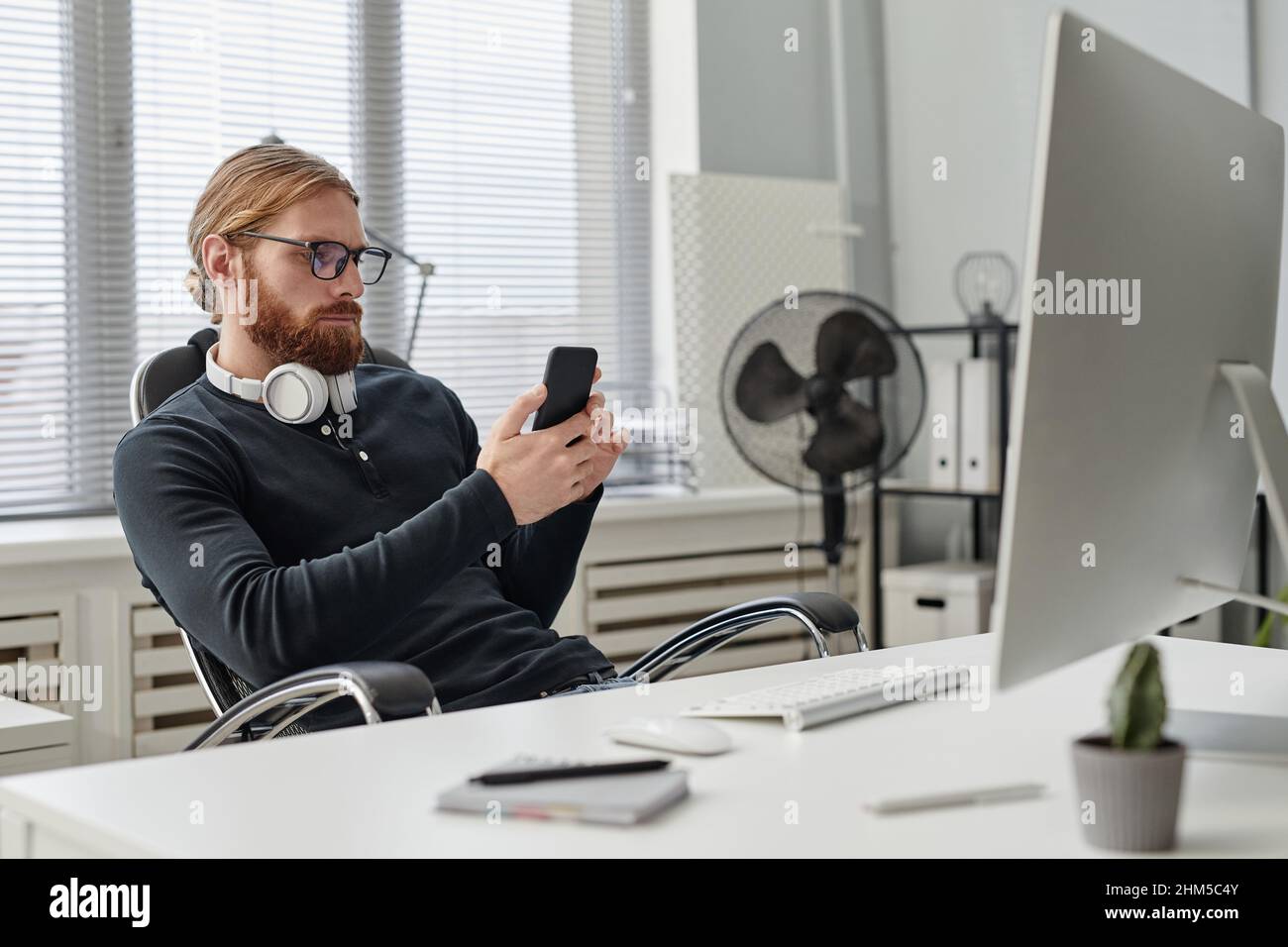 Young bearded businessman scrolling through contacts or messages in ...