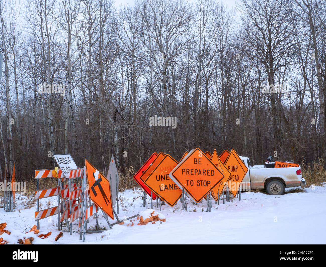 Orange Road Warning Signs stand in winter snow, near a Pilot Car pickup ...