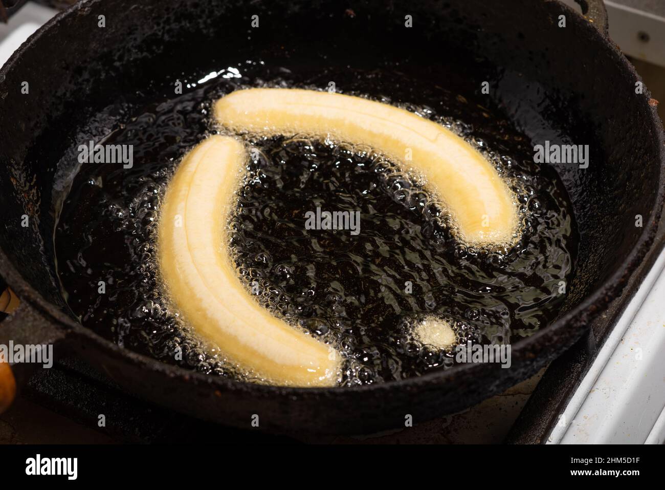 Fried bananas in a pan. Raw bananas boiled in oil Stock Photo - Alamy