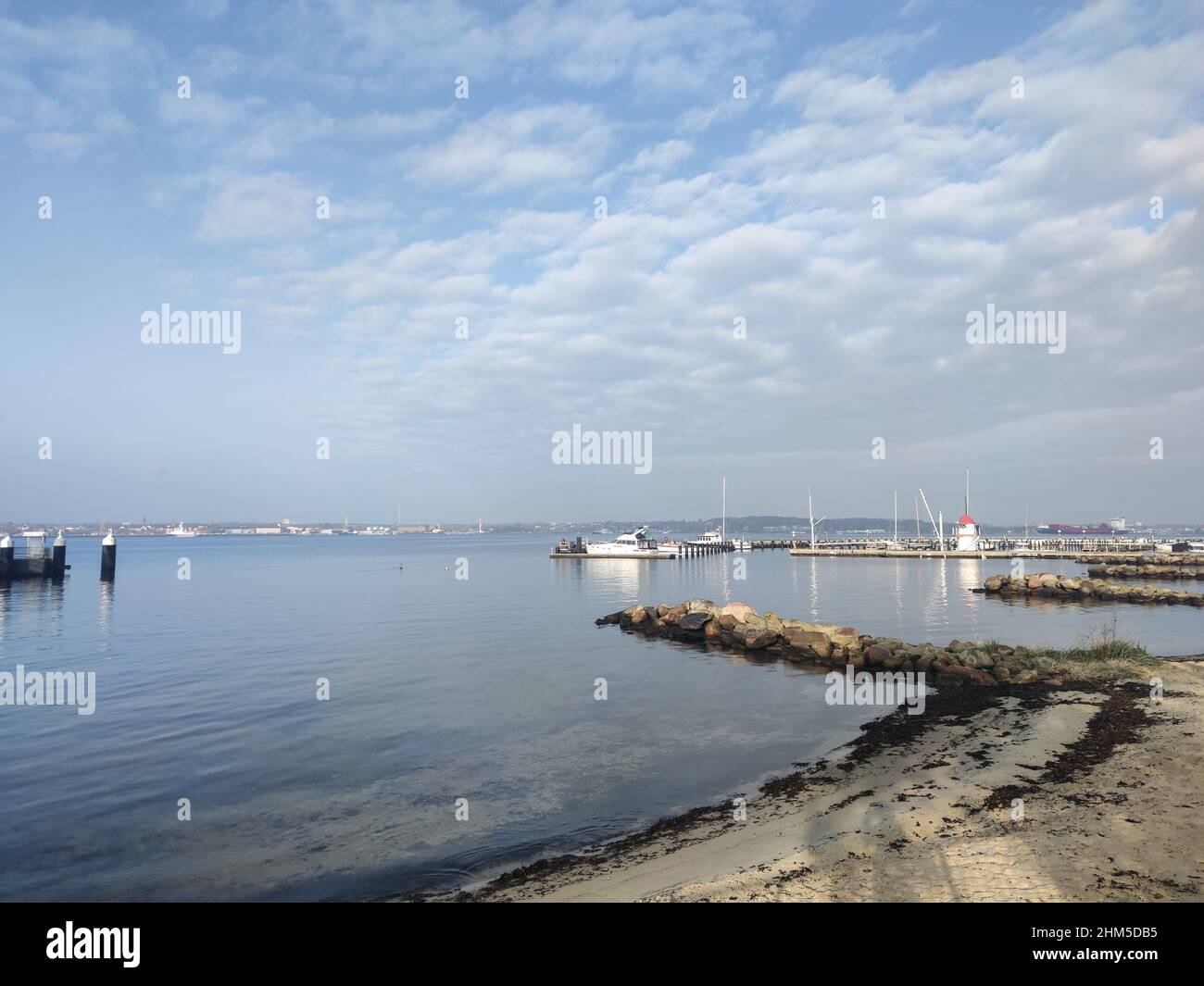 Sunset scene over Baltic sea with empty harbor and small lighthouse ...