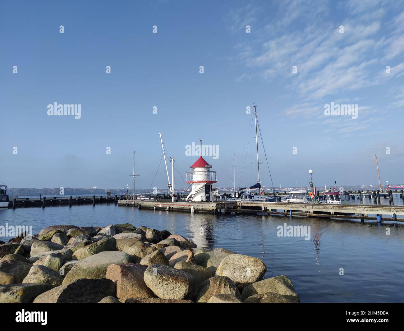 Sunset scene over Baltic sea with empty harbor and small lighthouse ...