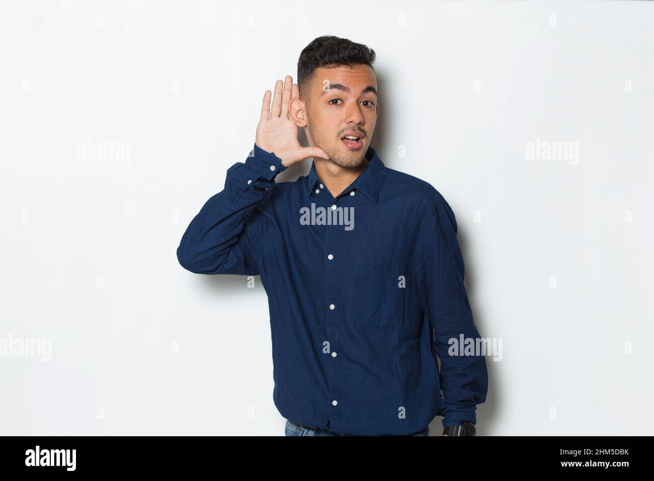 Young handsome business man with hand over ear listening an hearing to ...