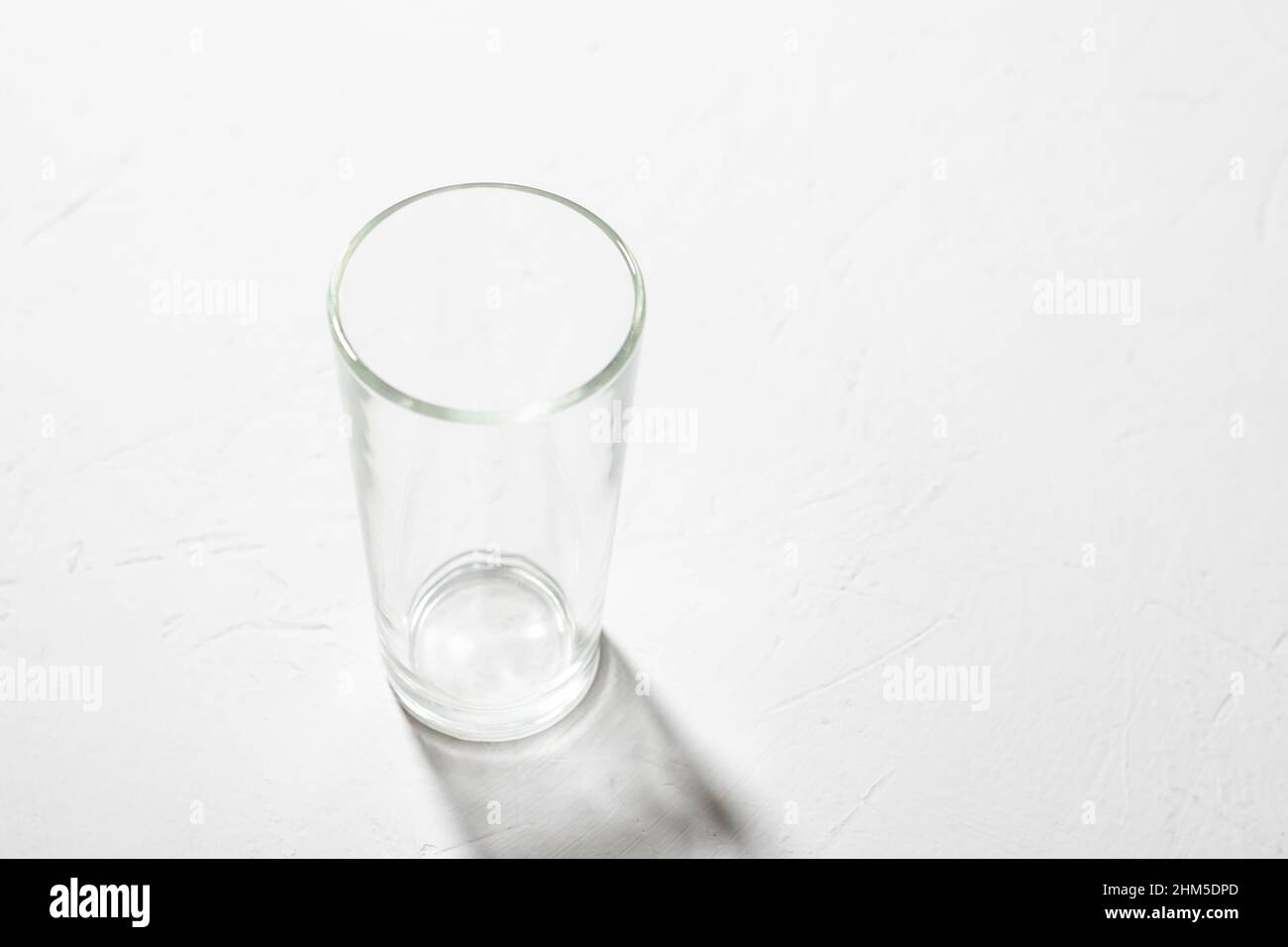 Empty glass beaker on a white background. Clear shadow, hard light ...