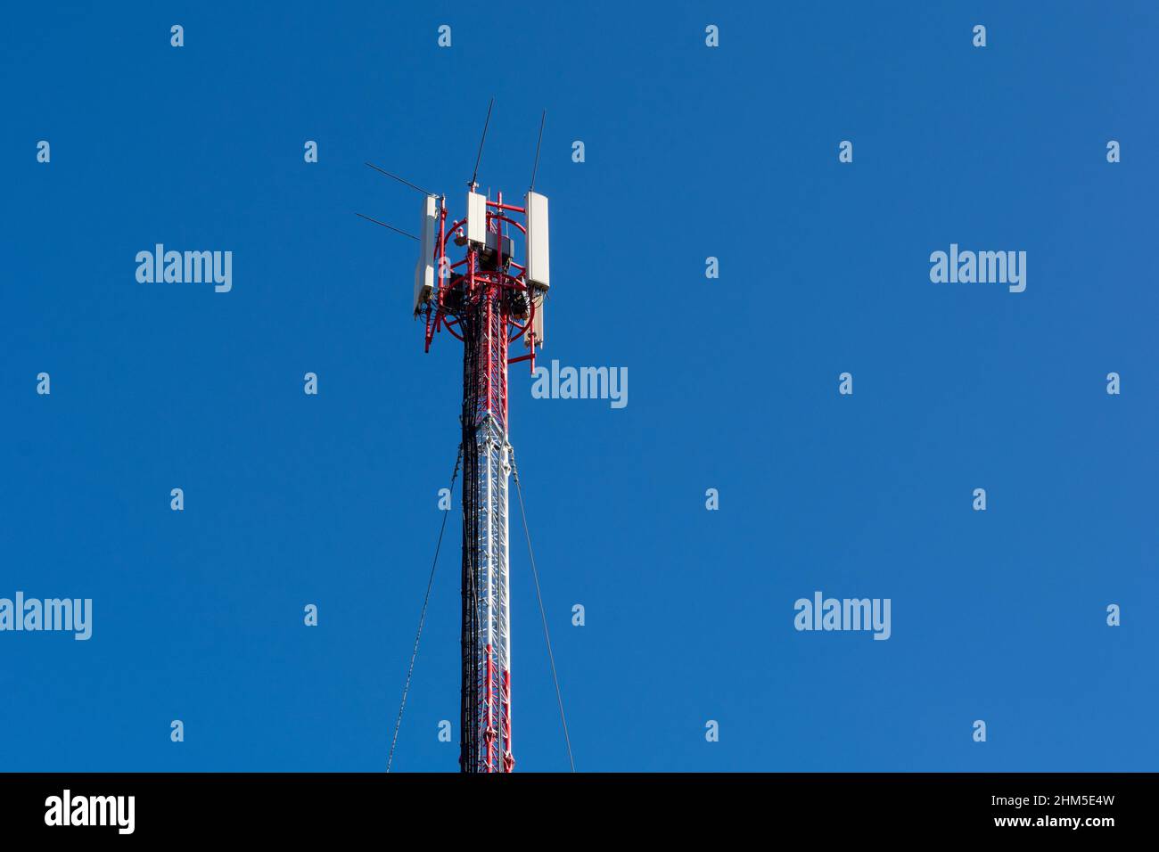 Telecommunication red tower with antennas and blue sky in the ...