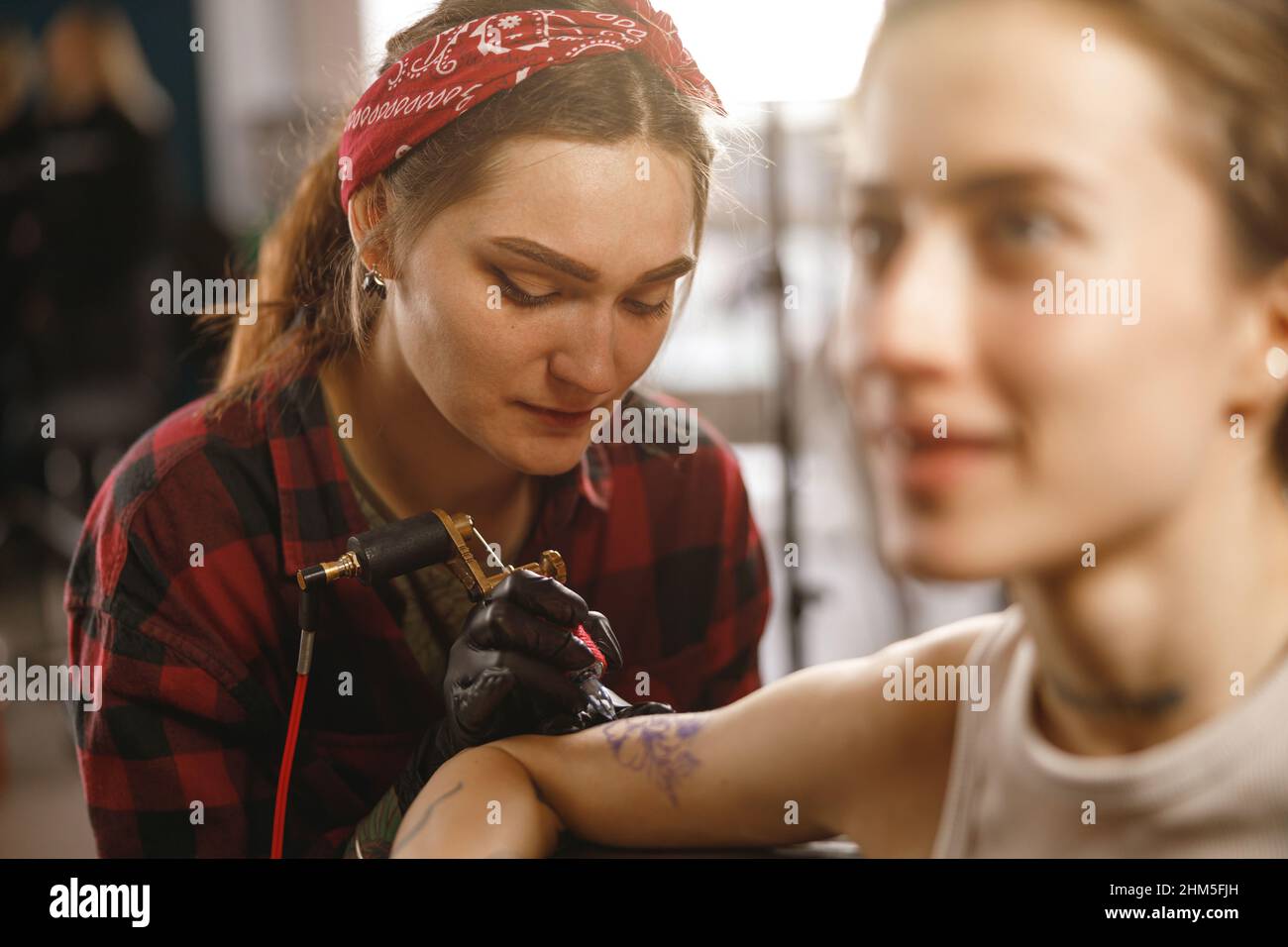 Focused female tattoo master making tattoo in salon Stock Photo - Alamy