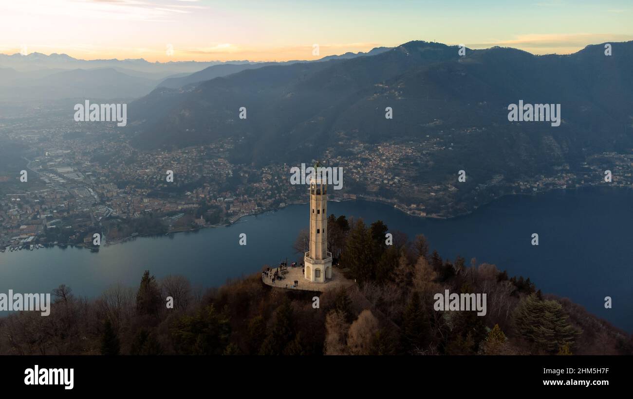 Aerial drone view of a lighthouse over Lake Como skyline with sunset ...