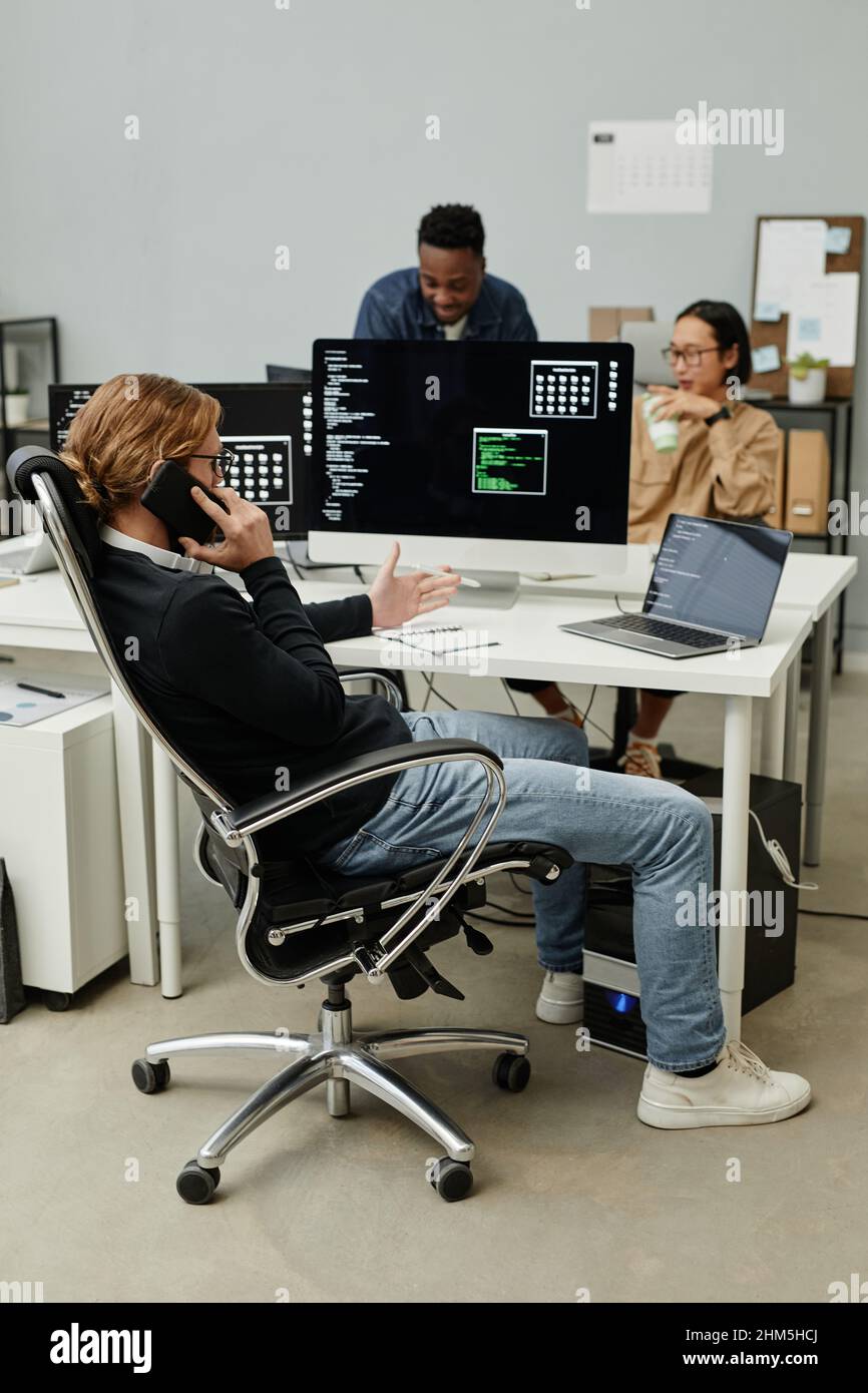 Young Caucasian male programmer calling by mobile phone by workplace ...