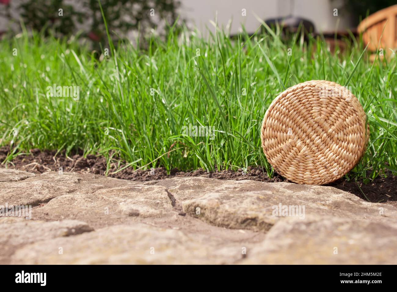 A rear view of an empty woven basket on its side on a stone walk and ...