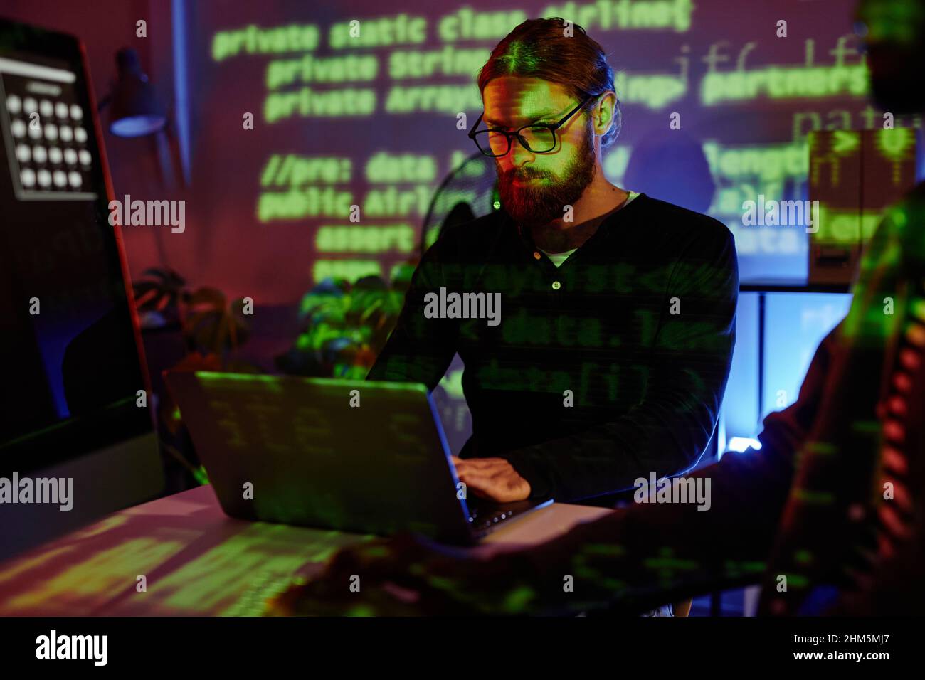 Serious bearded software developer looking at data on laptop screen ...