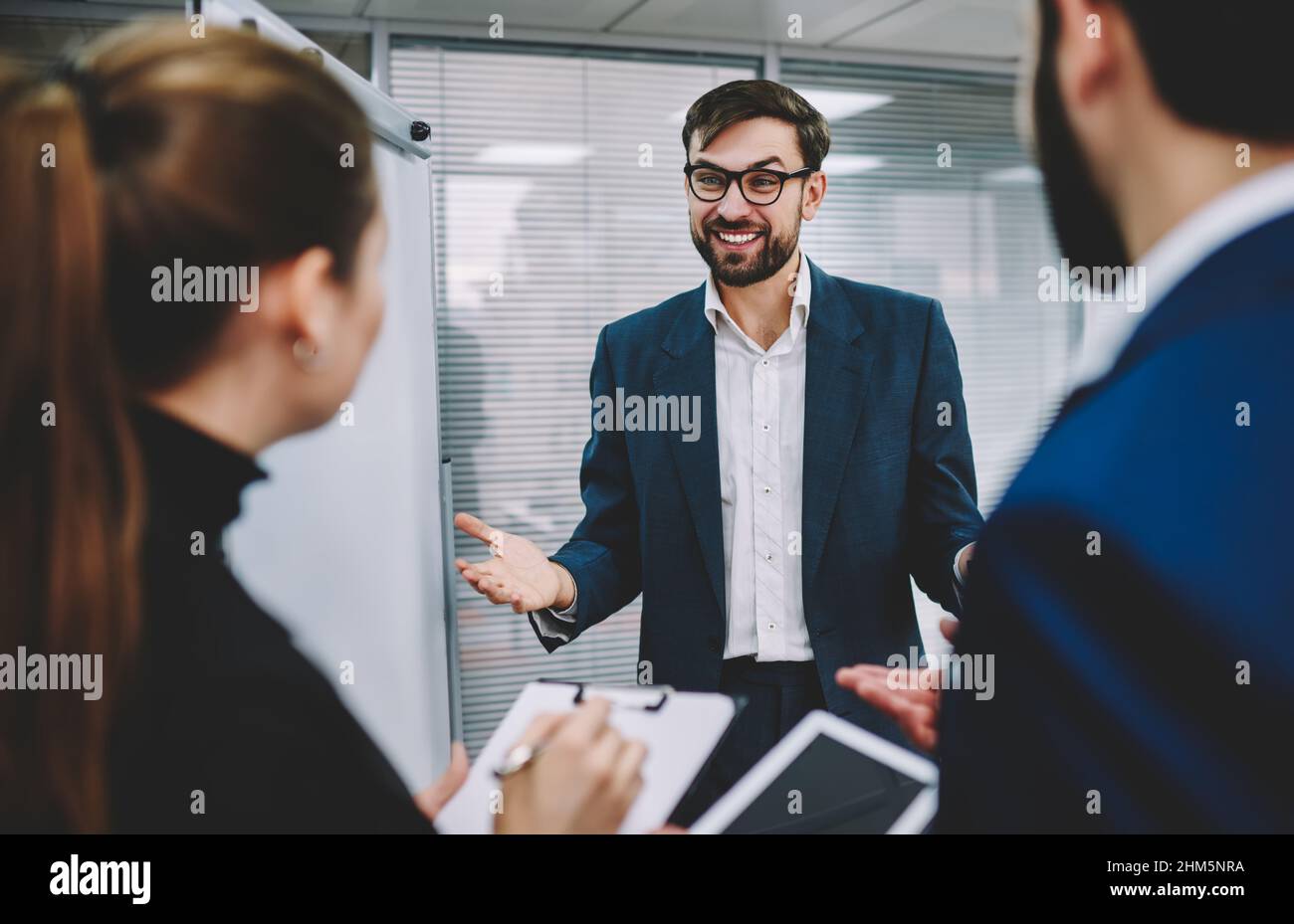 Smiling businessman communicating with colleagues in office Stock Photo ...