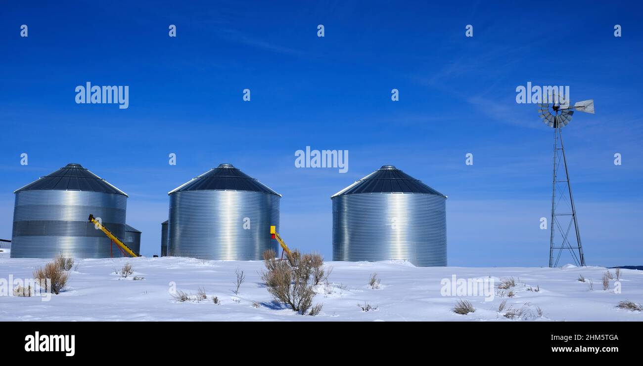 Windmill and steel grain silos in winter snow with blue sky on farm for ...