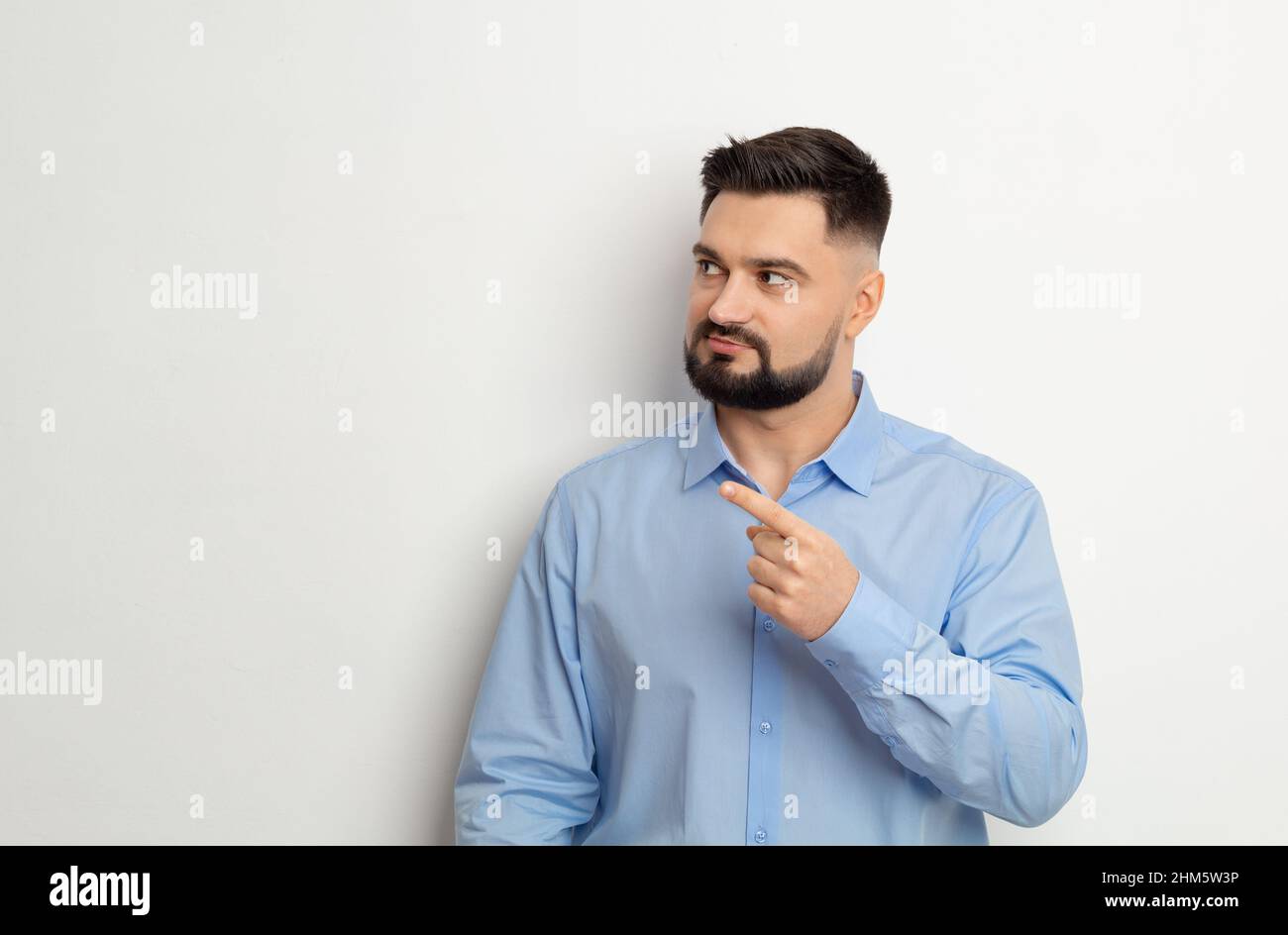Portrait of a man pointing his finger showing copy space on a white ...