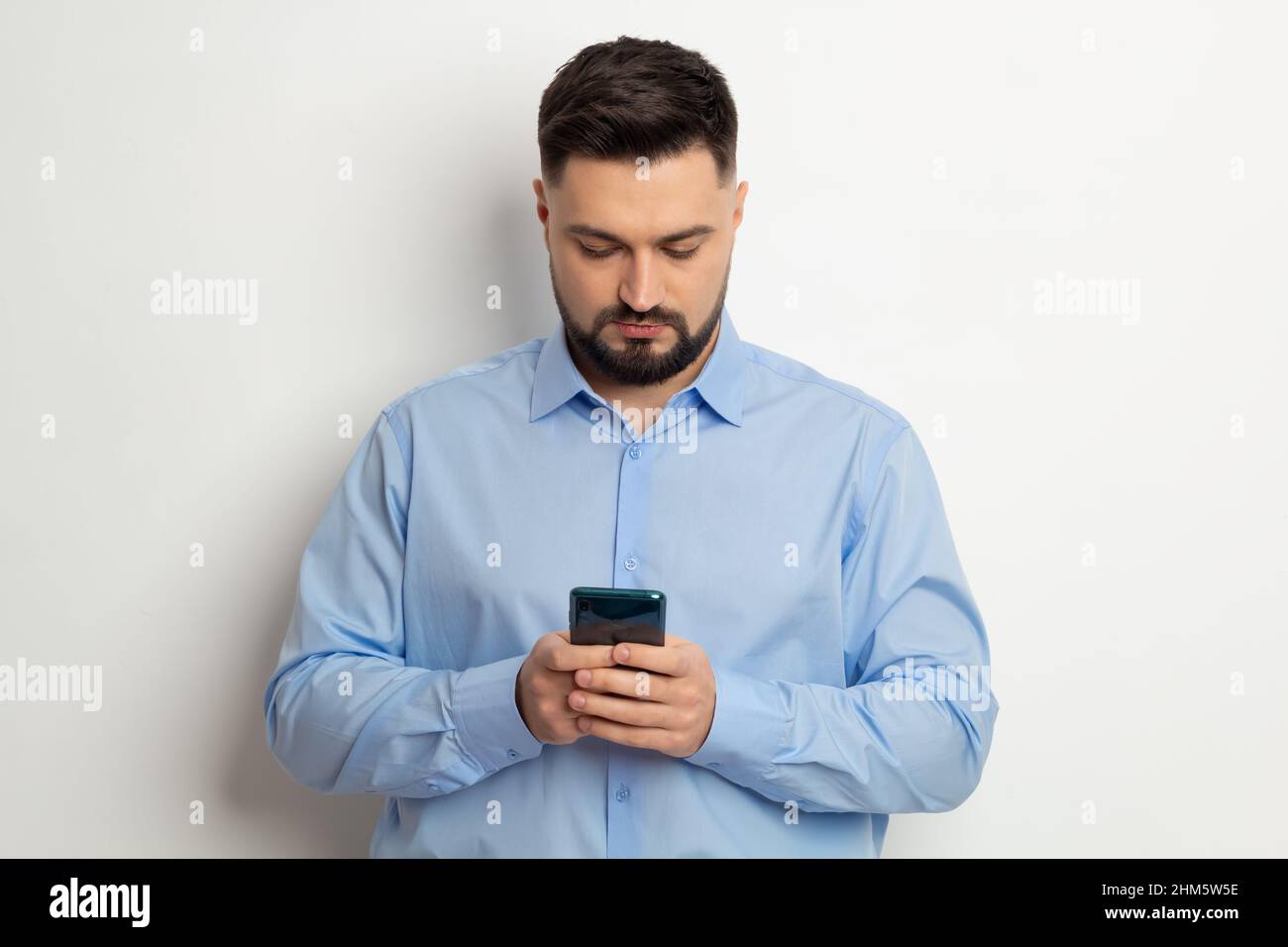 Portrait of a man using a mobile phone, smartphone standing on a white ...
