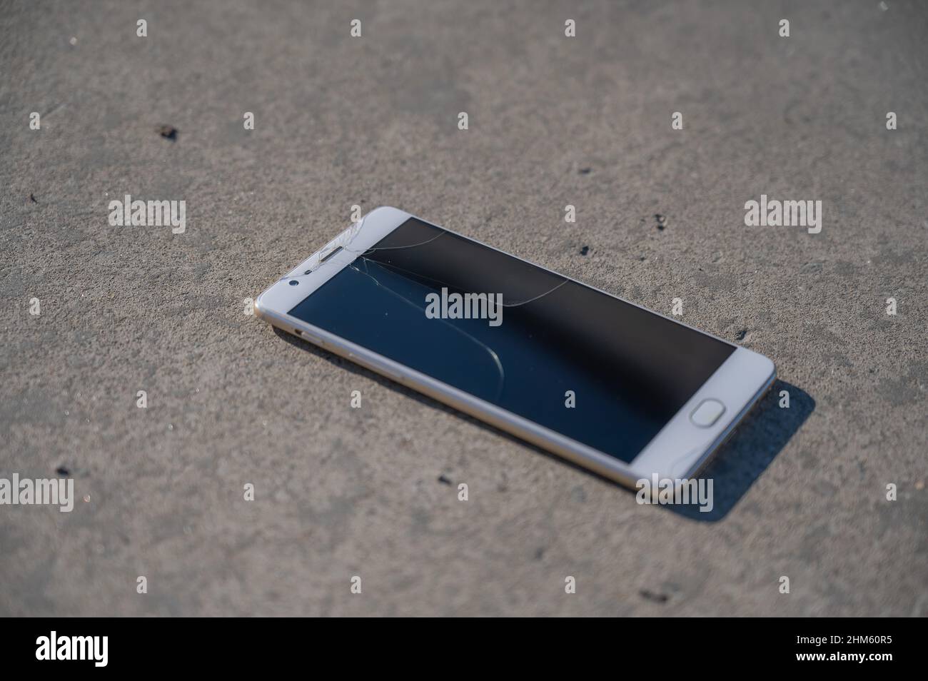 Phone with a broken screen on the pavement Stock Photo - Alamy