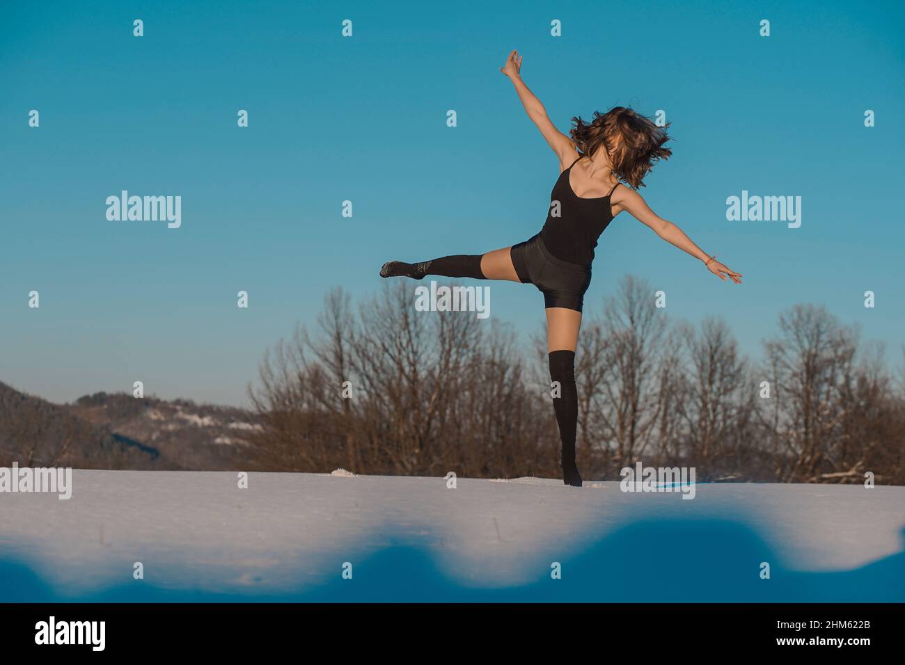 A young ballet dancer in training suit performing outdoors in ...