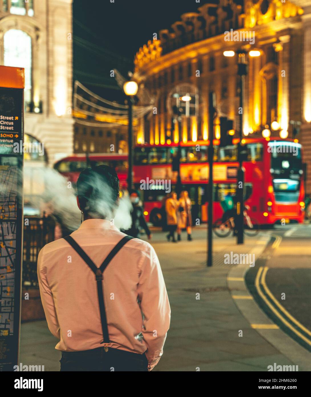 Vertical shot of a man smoking a vape in the background of a cityscape ...