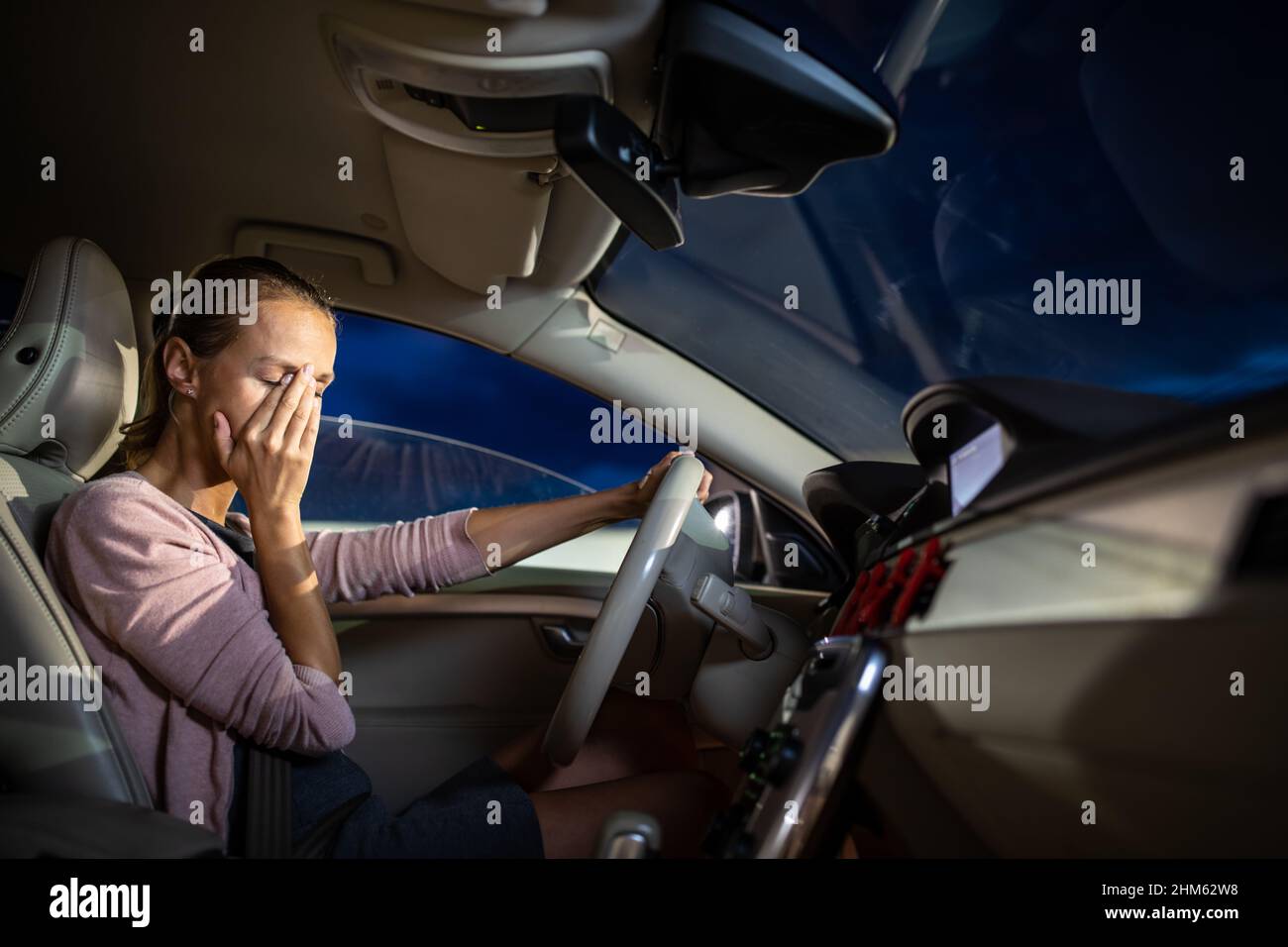 Young female driver at the wheel of her car, super tired, falling ...