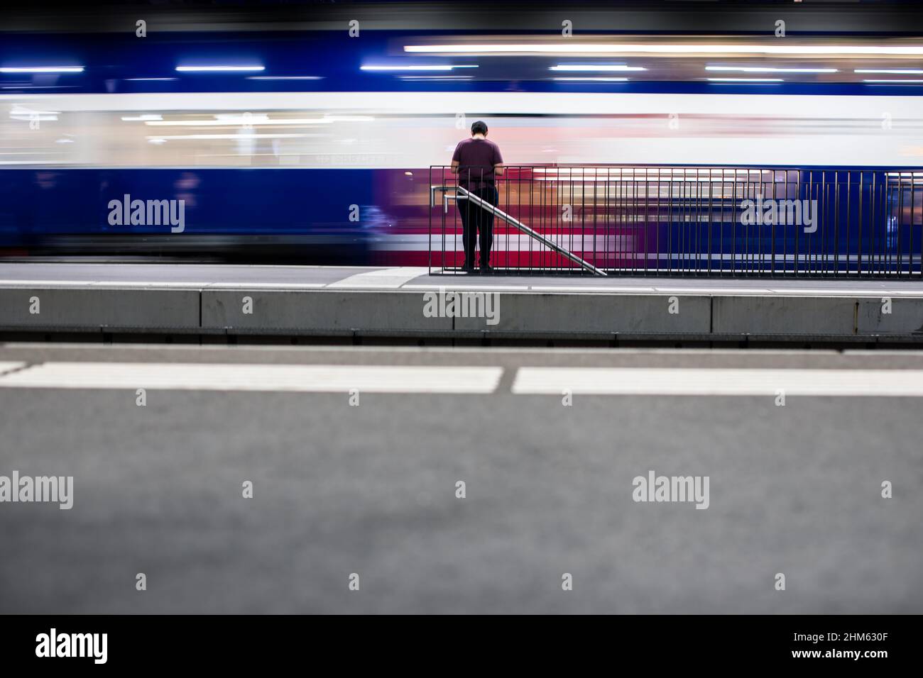 People in a trainstation with motion blurred trains moving fast (color ...