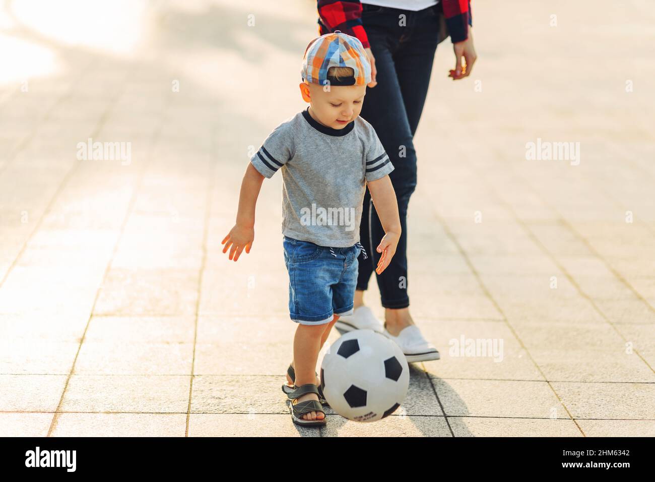 Mom and son play football together outdoors in the park, Little boy ...