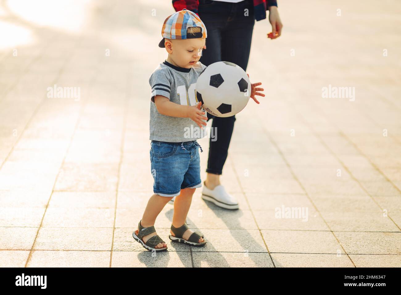 Mom and son play football together outdoors in the park, Little boy ...