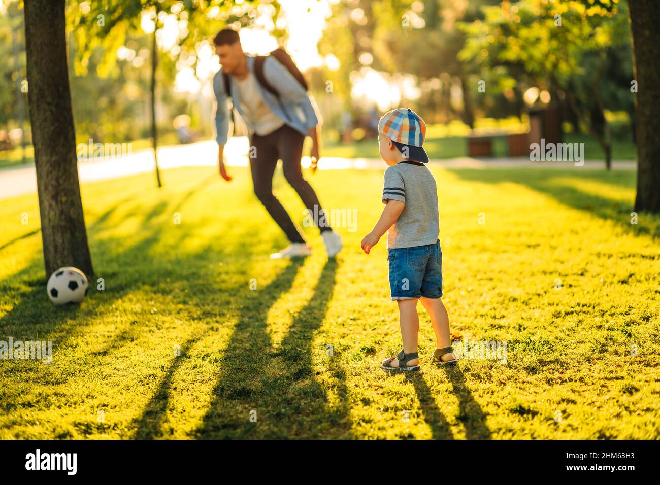 Dad and son with a soccer ball in a green park. Football field Father ...