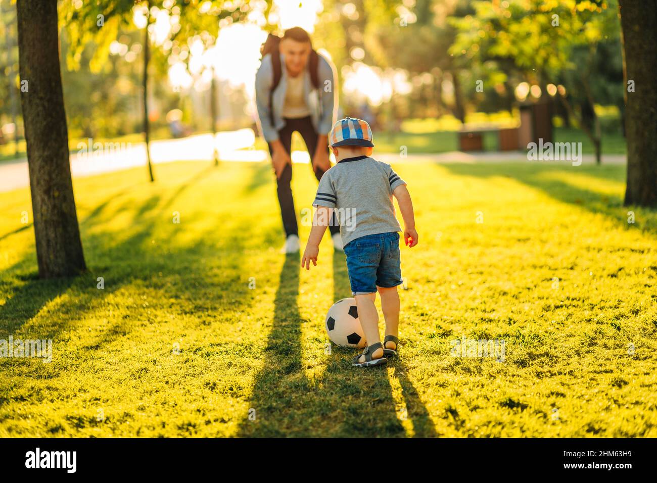 Dad and son with a soccer ball in a green park. Football field Father ...