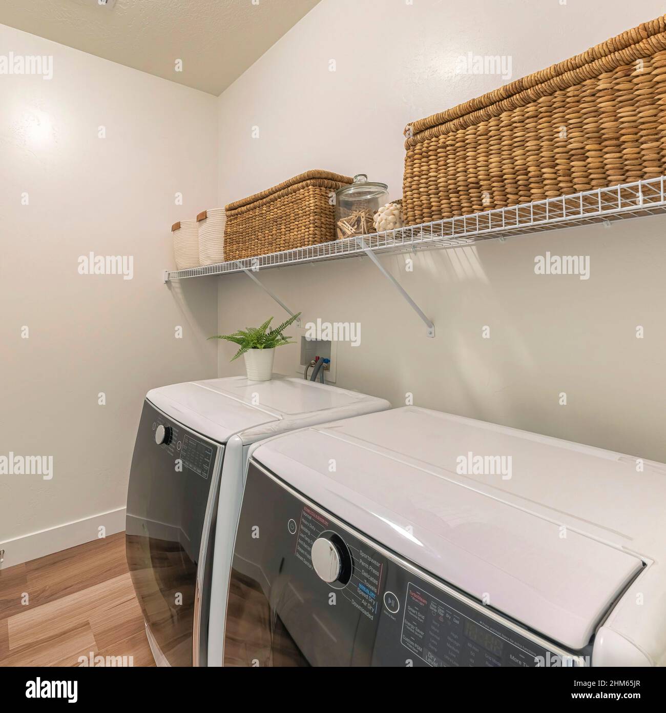 Square Laundry room with two laundry appliances and woven boxes on a ...