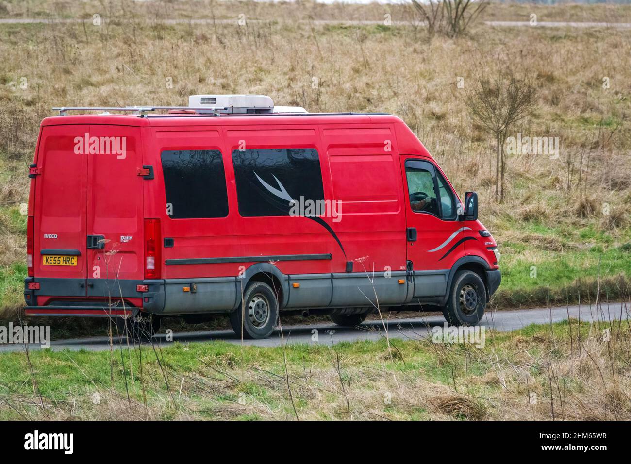a long wheel base Iveco Daily 355 2.3 HPI red van driving along a ...