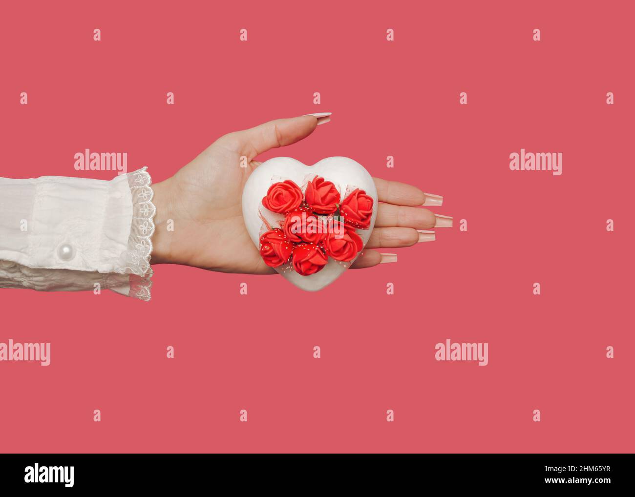 A woman's hand gives a white romantic heart decorated with small red ...