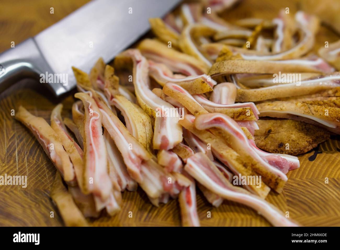 Selective focus on raw sliced ear of pork and chief knife on wooden ...