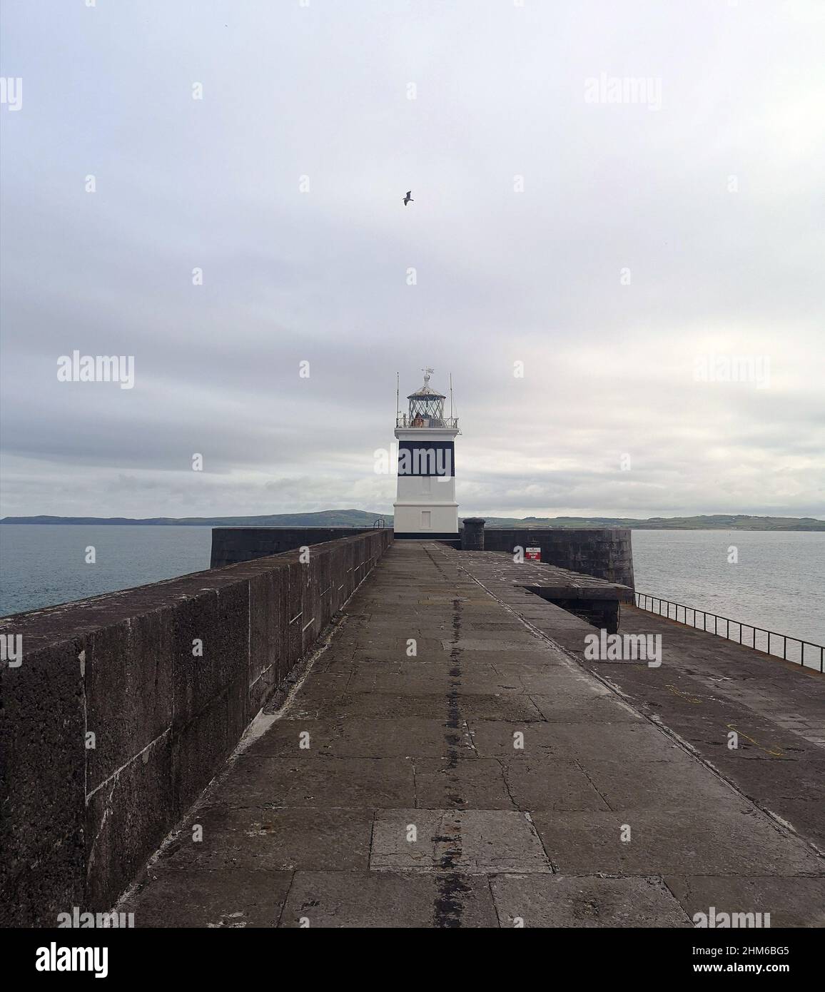 A vertical shot of the Holyhead Breakwater lighthouse on a concrete ...
