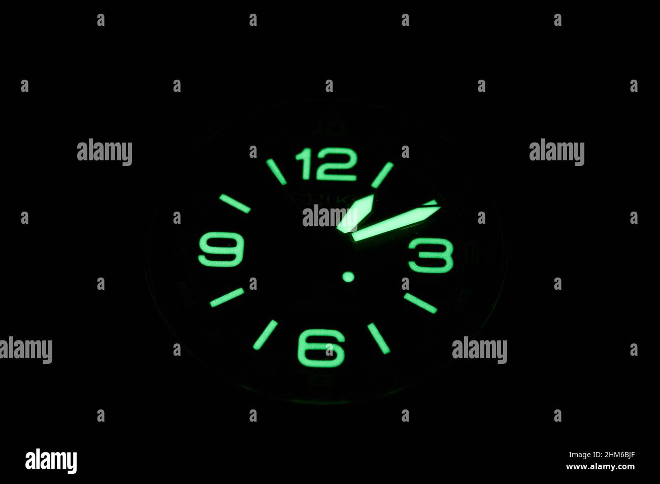 Closeup of the wristwatch neon clock face glowing in the dark on the ...