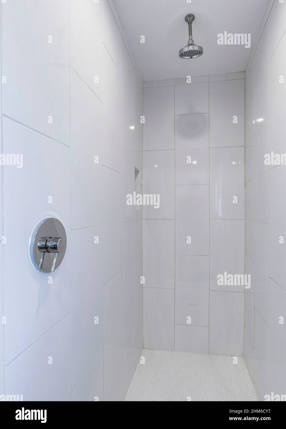 Vertical Narrow white shower room with white glossy tile surround Stock ...