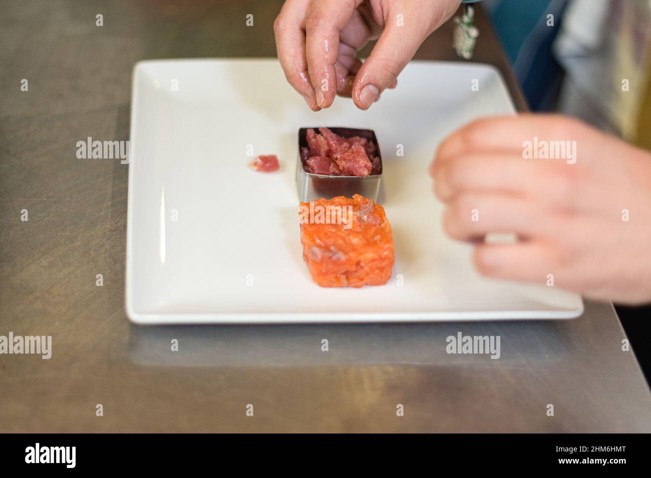 Chef preparing gourmet cubes of raw fish tartare with wild salmon and ...