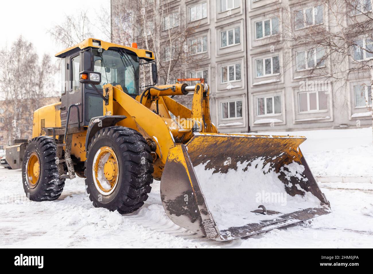 Big orange tractor cleans up snow from the road and loads it into the ...