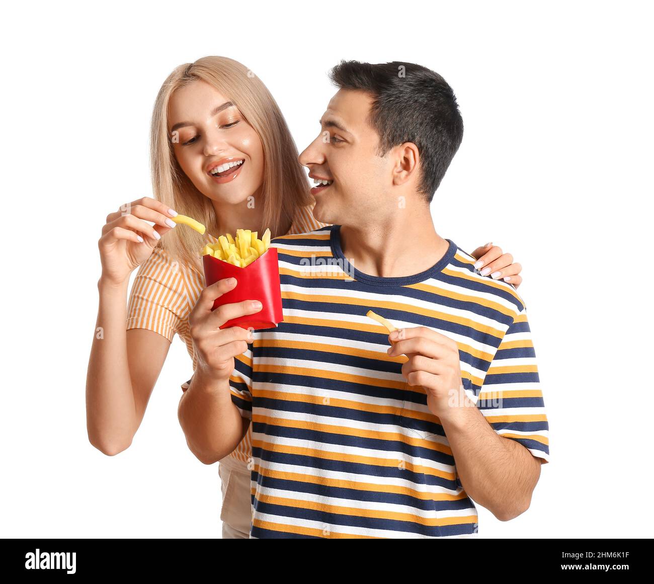 Young couple eating french fries on white background Stock Photo - Alamy