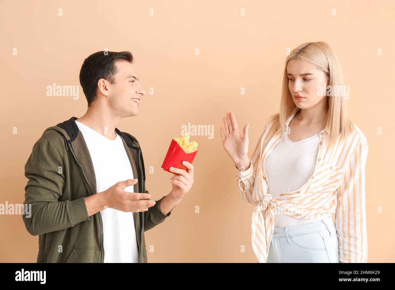 Young woman refusing to eat french fries on beige background Stock ...