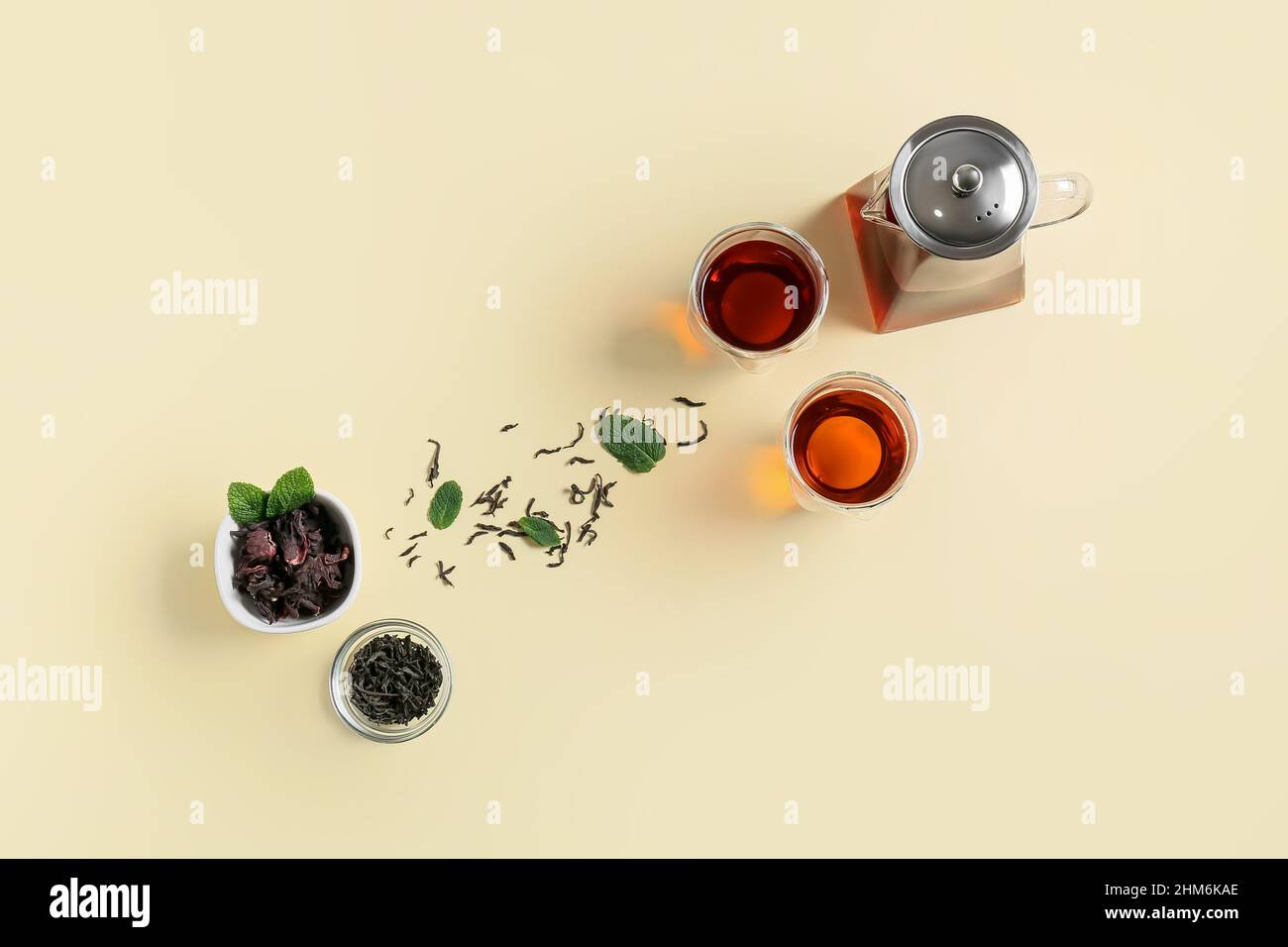 Composition of teapot and glass with tasty tea on yellow background ...
