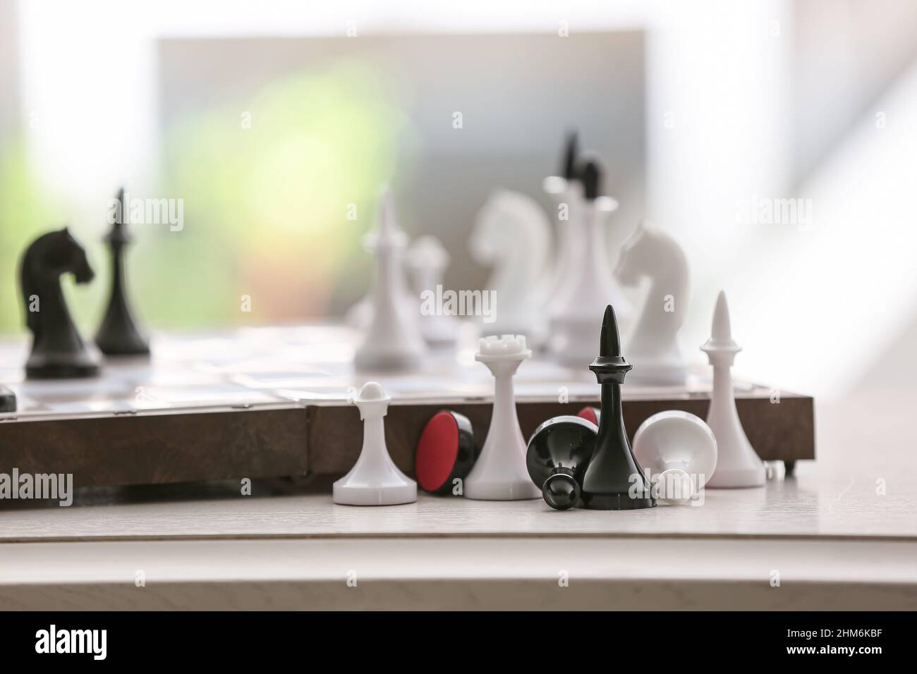Chess pieces with game board on table in room Stock Photo - Alamy