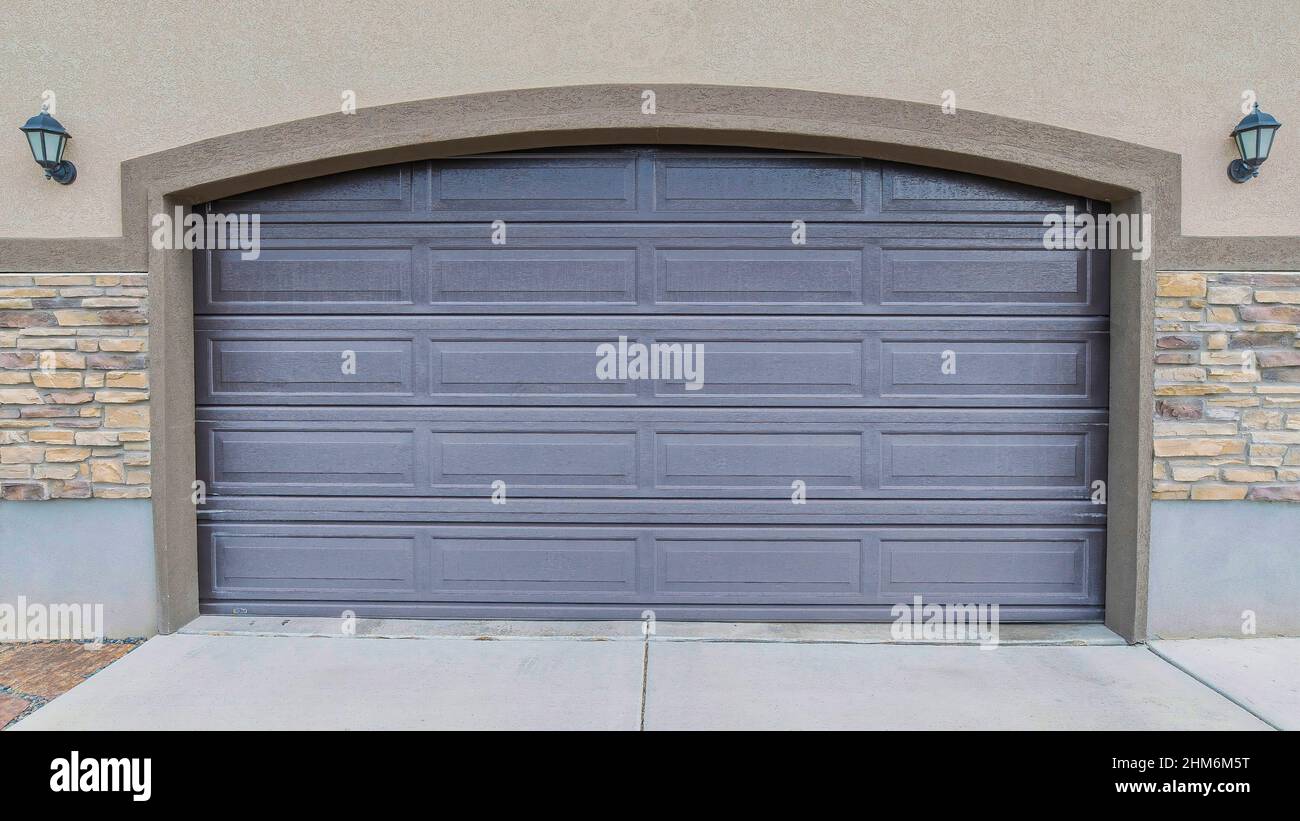 Panorama Exterior of an arched gray garage door with two wall lamps on ...