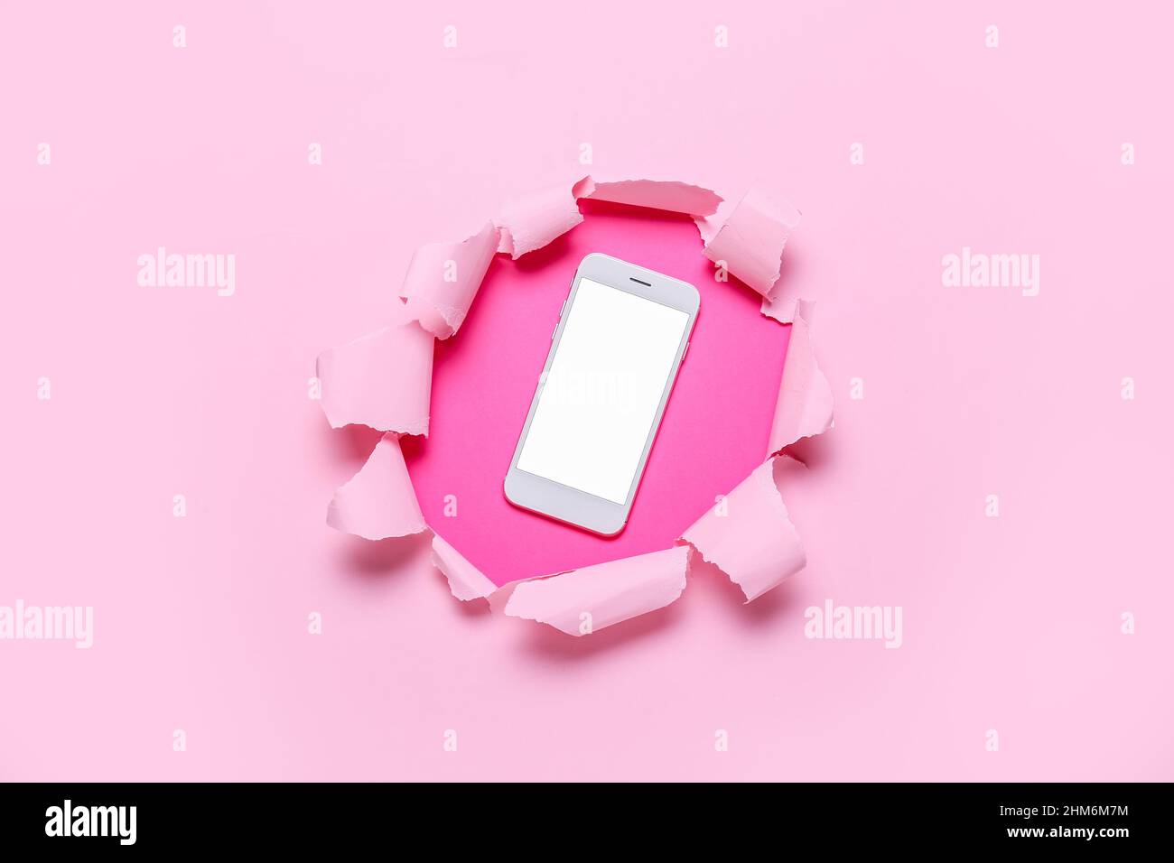 Mobile phone visible through torn color paper Stock Photo - Alamy