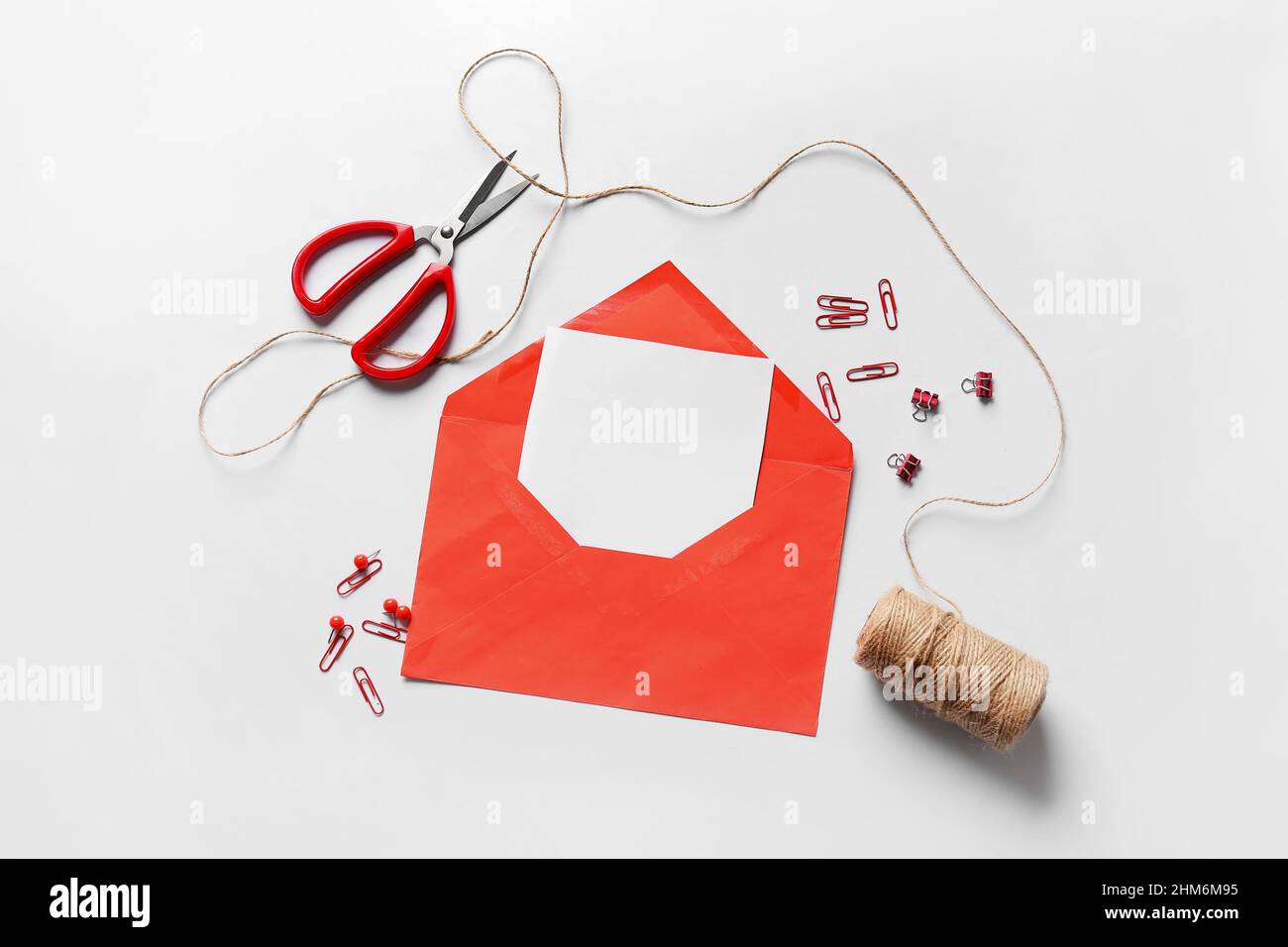 Envelope with blank card, stationery, rope and scissors on white ...