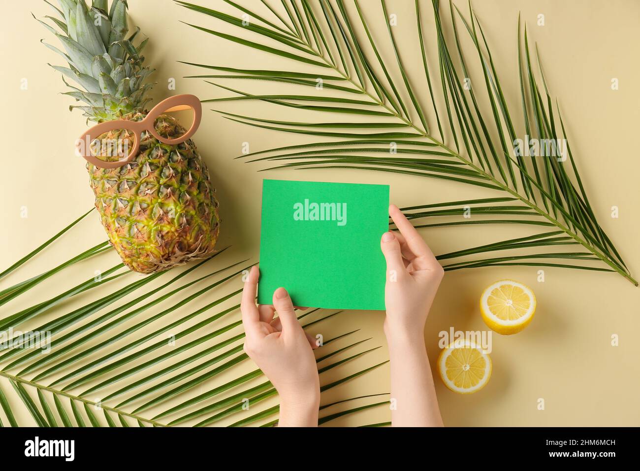 Female hands with blank card, palm leaves, sunglasses and fruits on ...