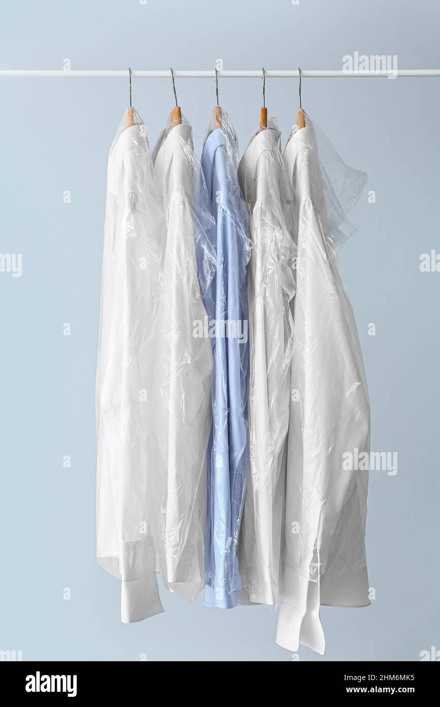 Rack with clean shirts in plastic bags on grey background Stock Photo ...