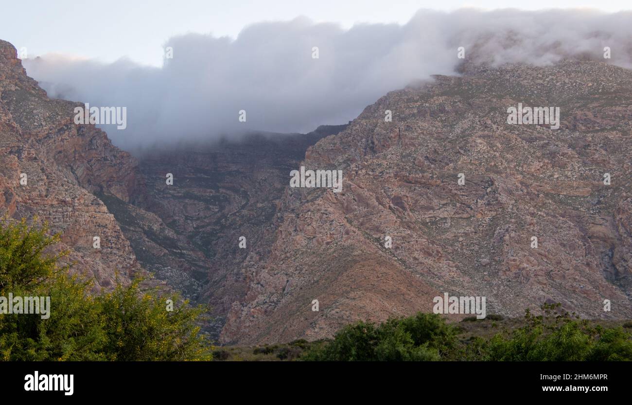 Misty clouds build up at the top of a mountain and blow down a natural ...