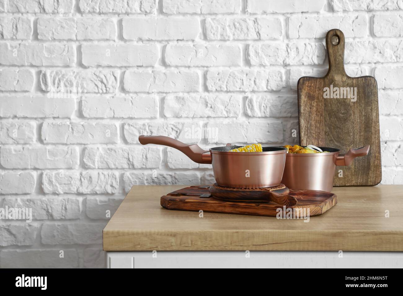 Sauce pan, cooking pot with prepared food and wooden boards on table ...