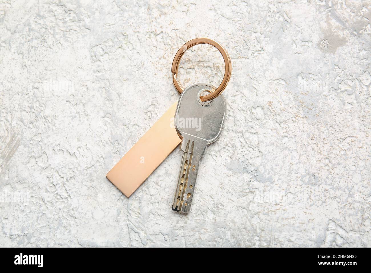 Key with stylish bronze keychain on light background Stock Photo - Alamy